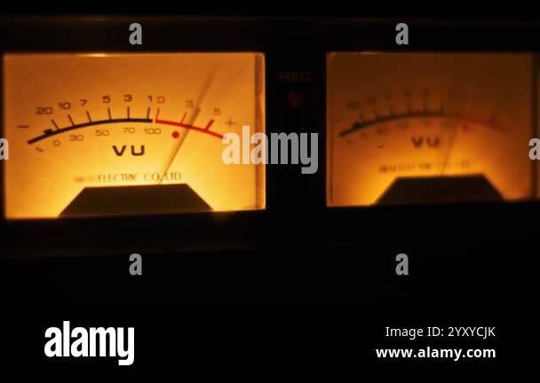 Illuminated close-up of vintage VU meters on an analog audio recorder ...