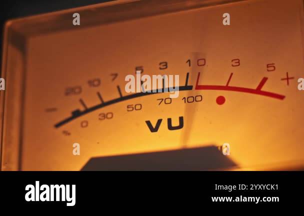 A macro shot of a vintage VU meter lit by warm ambient light, capturing ...