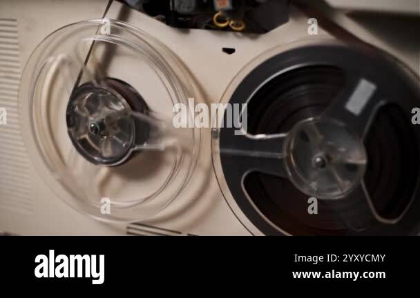 A high-definition close-up of a reel-to-reel recorder in operation ...