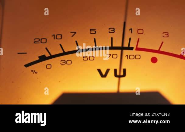 A warm close-up of a vintage VU meter glowing in soft light ...