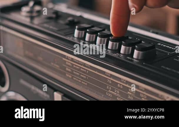 A finger activates the play button on a vintage stereo system, a symbol ...