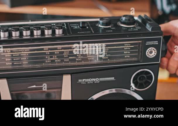 A hand carefully tunes a retro radio dial, searching for a clear signal ...