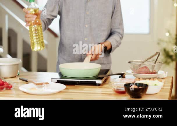Middle aged man pouring cooking oil and scooping cooked rice into a pan ...