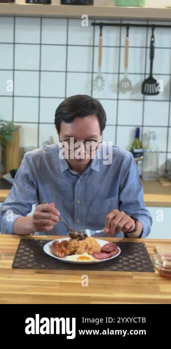 Happy middle aged man eating fried rice with sunny side up egg and ...