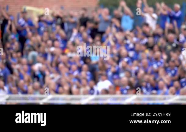 Many fans supporting soccer team at stadium. Blurred crowd of people at ...
