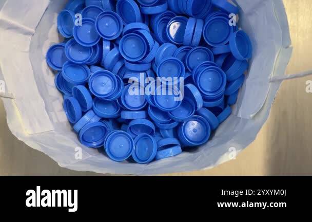 Dozens of plastic blue caps from a water bottle in a cardboard bag ...