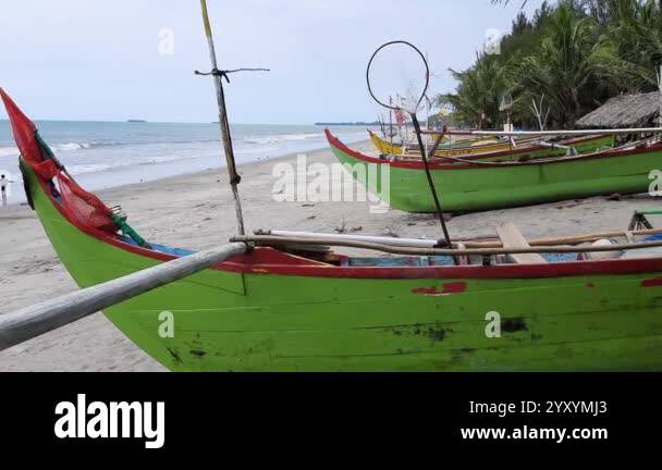 Traditional green fishing boats lined up on the sandy shore of Gasan ...