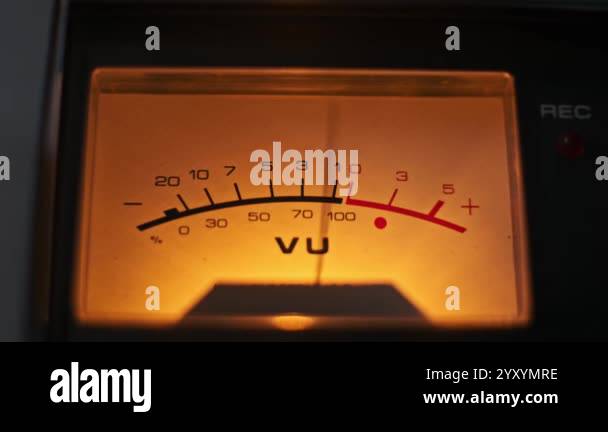 A close-up view of a vintage VU meter glowing warmly, highlighting its ...