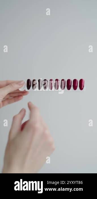 Close-up of a hand selecting a nail polish color from a sample palette ...