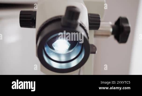 Detailed close-up of a modern microscope lens illuminated in a white ...