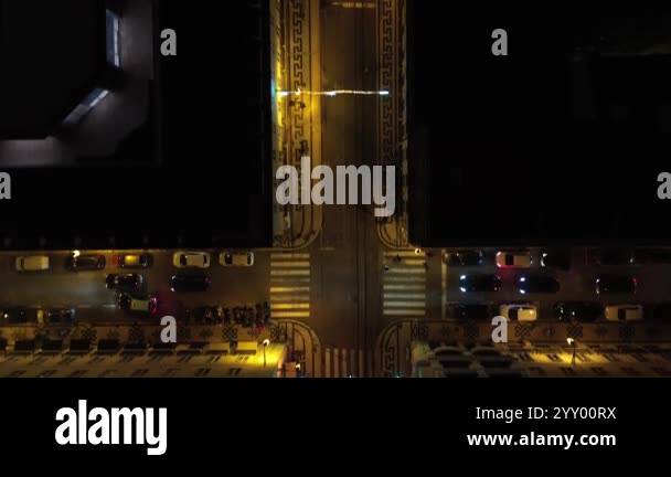 A drone flies above a city street at night, over the roofs and ...