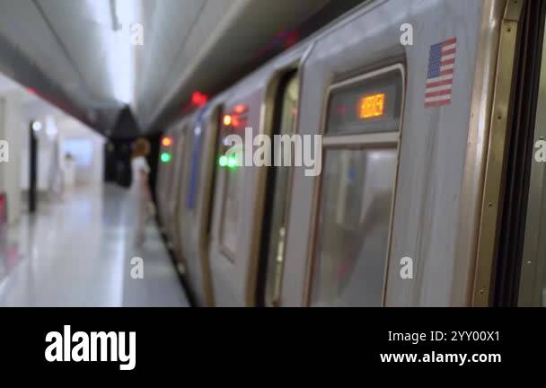 A tranquil subway station shows a waiting train and a minimal crowd ...