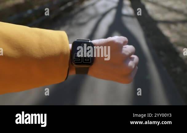 A vibrant smartwatch on a hand displays the time, basking in sunlight ...