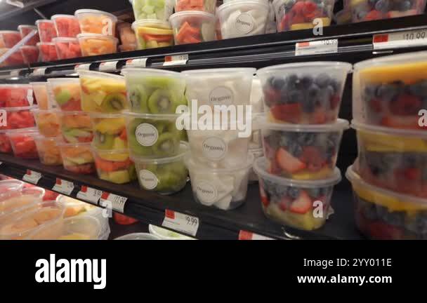 A colorful and assorted variety of fresh fruit cups are neatly arranged ...