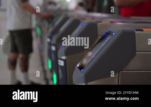 Passengers using automated turnstiles at a busy transportation hub ...
