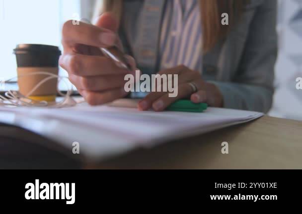 A woman is sitting at a desk with a pen and a cup of coffee. She is ...