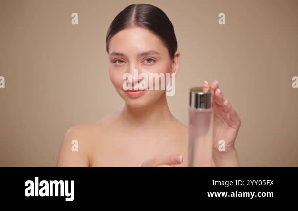 Smiling woman holds bottle with cosmetic tonic. Video of attractive ...