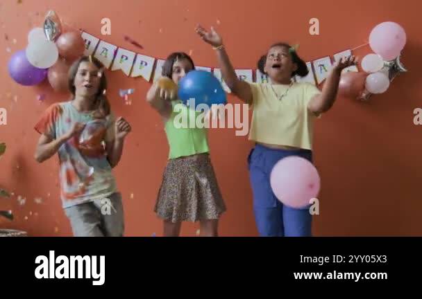 Three positive multi-ethnic gen alpha children dancing under confetti ...