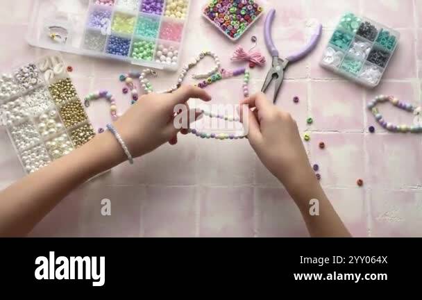 Artist carefully strings letter beads onto a thread, creating a ...