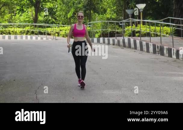 A woman is running on a beautiful winding road that is surrounded by ...