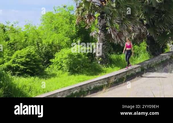 A woman is running on a beautiful winding road that is surrounded by ...