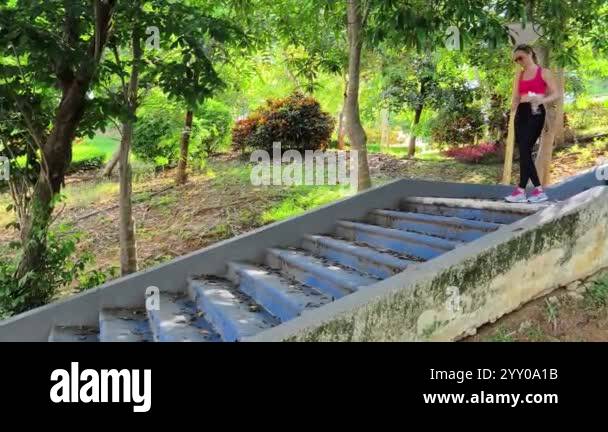 A woman is running on a beautiful winding road that is surrounded by lush greenery and stunning ...