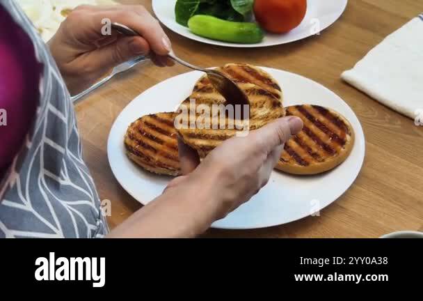 A skilled chef cooking grilled chicken burgers at the modern kitchen ...