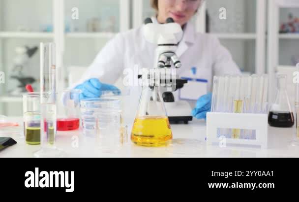 Qualified woman researcher adjusts settings of microscope. Scientist ...
