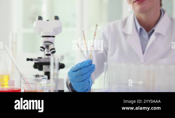 Woman laboratory technician shows pH test strips to colleague ...