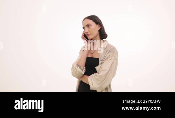 Young woman ends phone call expressing confusion on white background ...