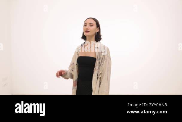 Surprised young woman waves hand greeting friend against white ...