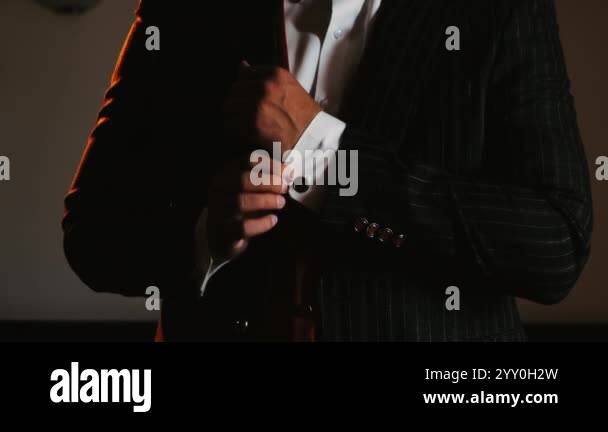 Close-up of a male businessman in a suit adjusting his shirt cuff. An ...