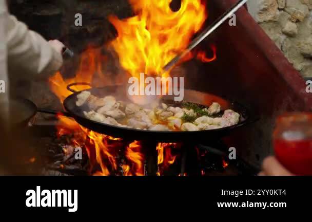 Process of mixing chicken pieces of Paella in frying pan. Chefs prepare ...
