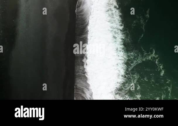 Foaming ocean waves covers beach with dark sand creating smooth surface ...