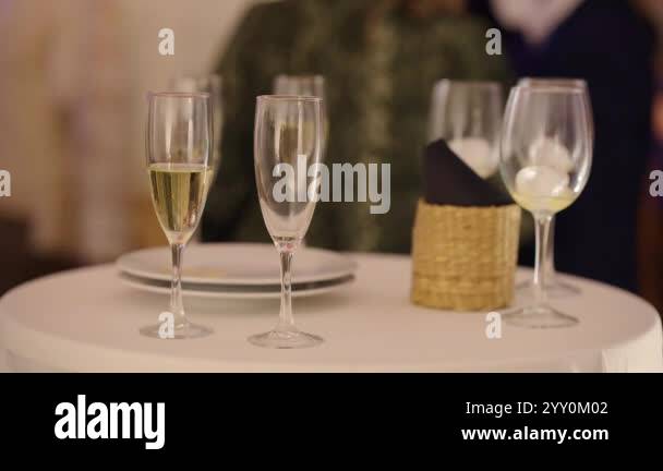 Wineglasses with luxury drinks and plates on small round table in ...