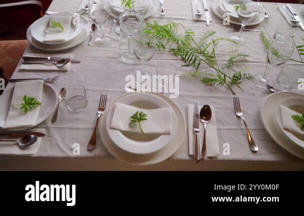 Table setting with tablecloth and dishes before guests arrive. Cutlery ...