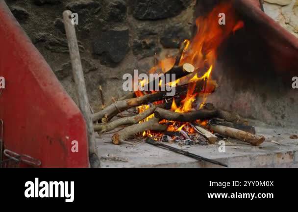 Process of making charcoal using fire in outdoor furnace near brick ...