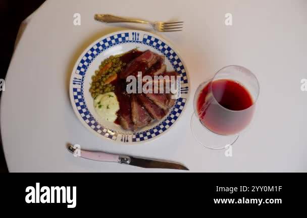 Delicious sliced steak served with vegetables and red wine in ...
