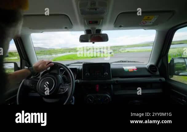 Bearded man driver navigates car along asphalt road. Focused young guy ...
