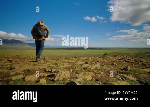 Man tourist with backpack carefully descends from rocky hill ...