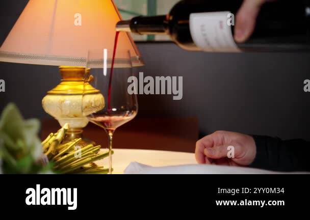 Waiter pours red wine into guest glass in vintage restaurant closeup ...