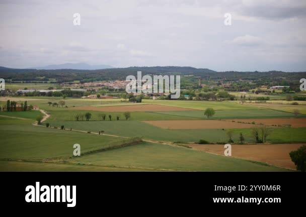 Green farm fields against old Girona town under cloudy sky aerial view ...