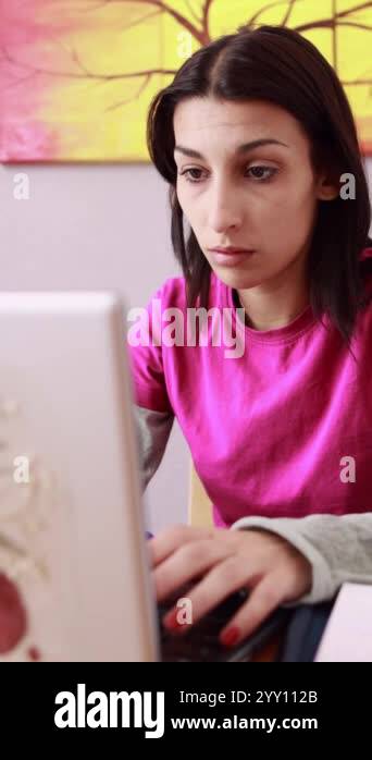 Young woman concentrating on work while typing on a laptop at home ...