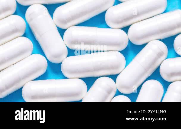 lot of white pills, capsules, vitamins, drugs on pink color background ...