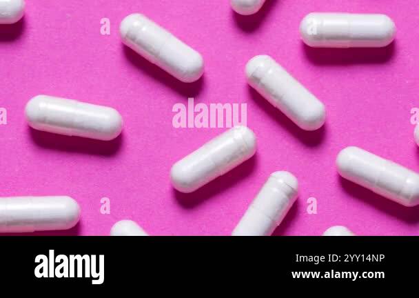 lot of white pills, capsules, vitamins, drugs on pink color background ...
