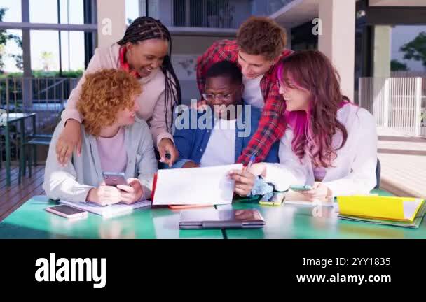 happy students sit together at a table, collaborating and discussing ...