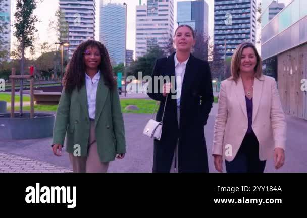 Three professional women walk together through a contemporary cityscape ...