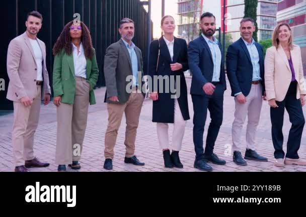 A diverse group of professionals stands together outdoors, smiling and ...