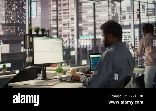 African american company worker taking a break to stretch his back in the office, trying to ...