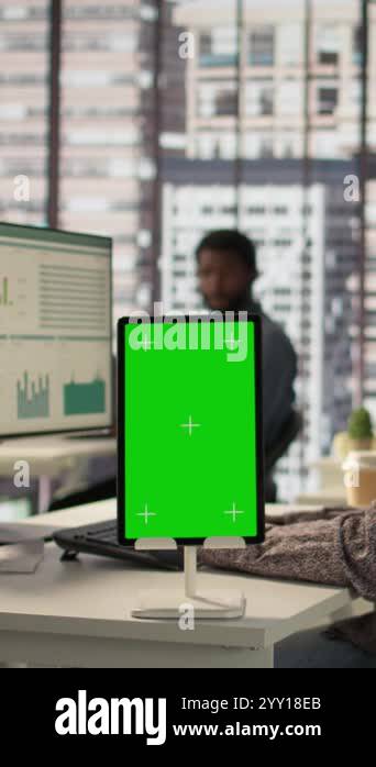 Vertical Video Female manager seated at workstation with green screen ...